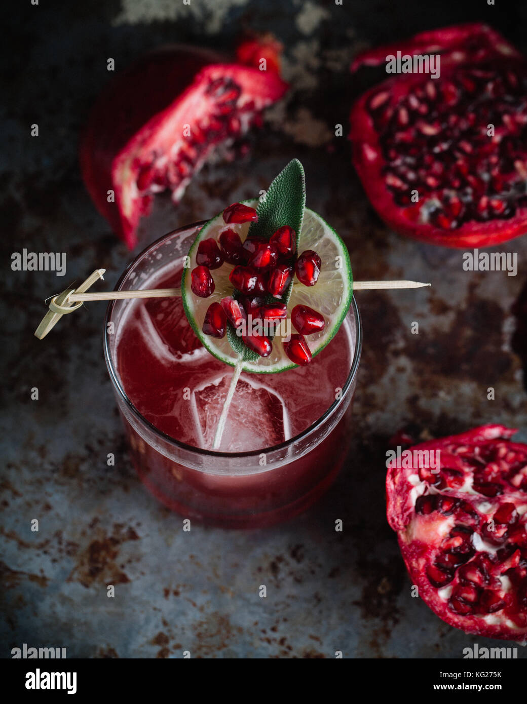 Alcoholic cocktail garnished with pomegranate seeds on dark moody ...