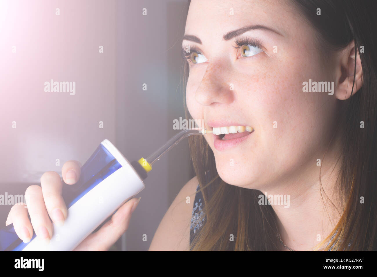 A woman using an oral irrigator in bathroom Stock Photo - Alamy