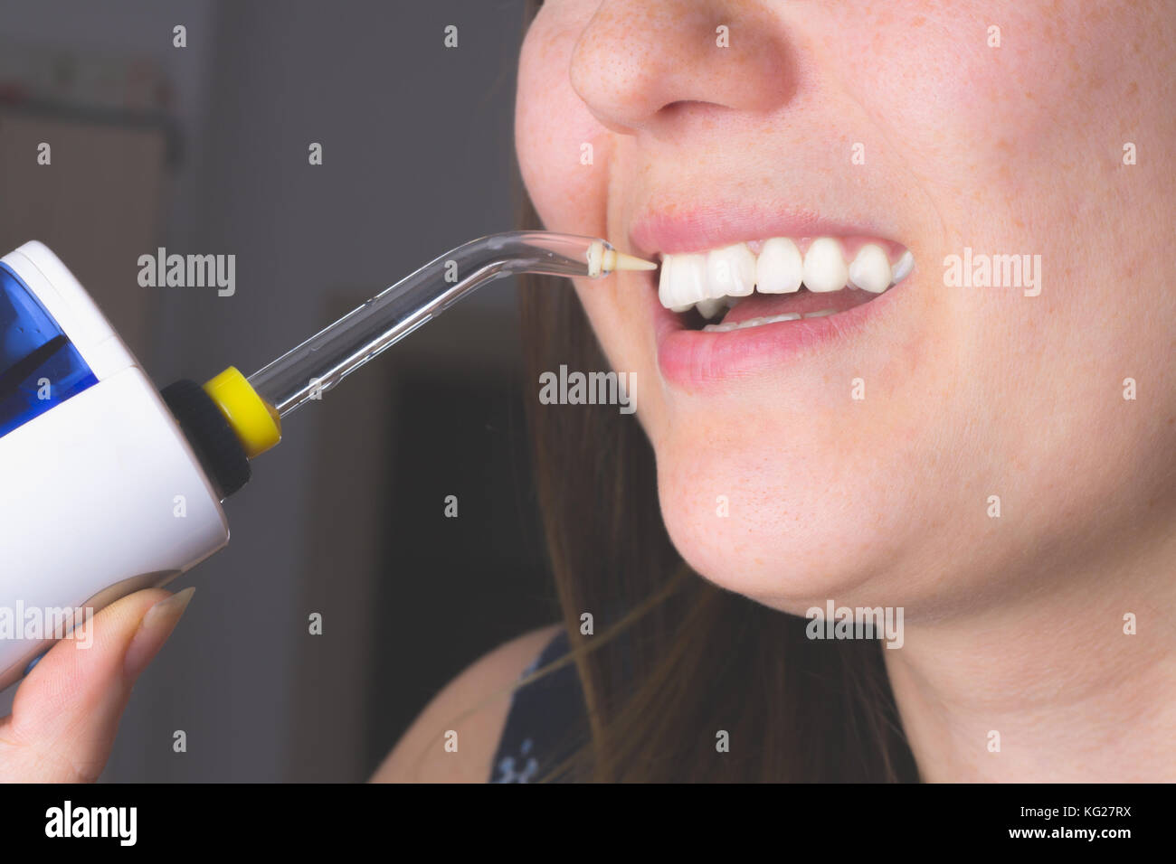 A woman using an oral irrigator in bathroom Stock Photo - Alamy