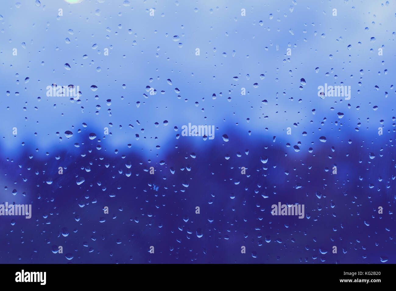 Rain on a glass. Drops of water on the glass. Night rain. Dark and blue ...