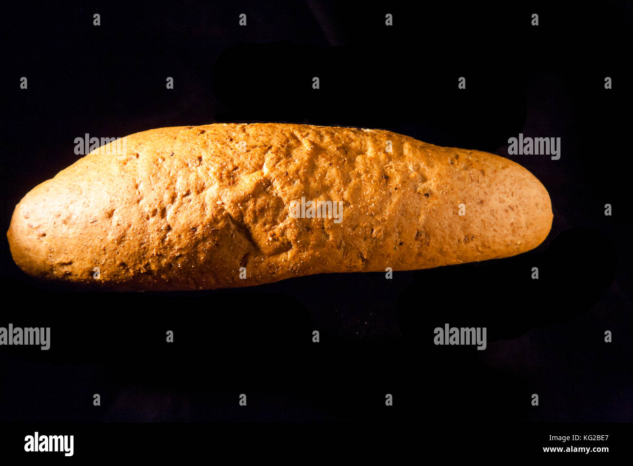 baton of brown bread on black background Stock Photo - Alamy