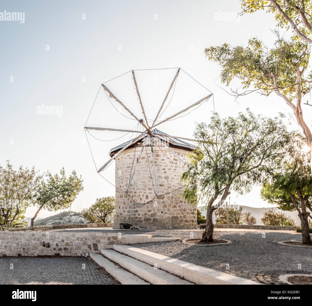 View of ancient stone windmill on clean blue sky background and trees ...