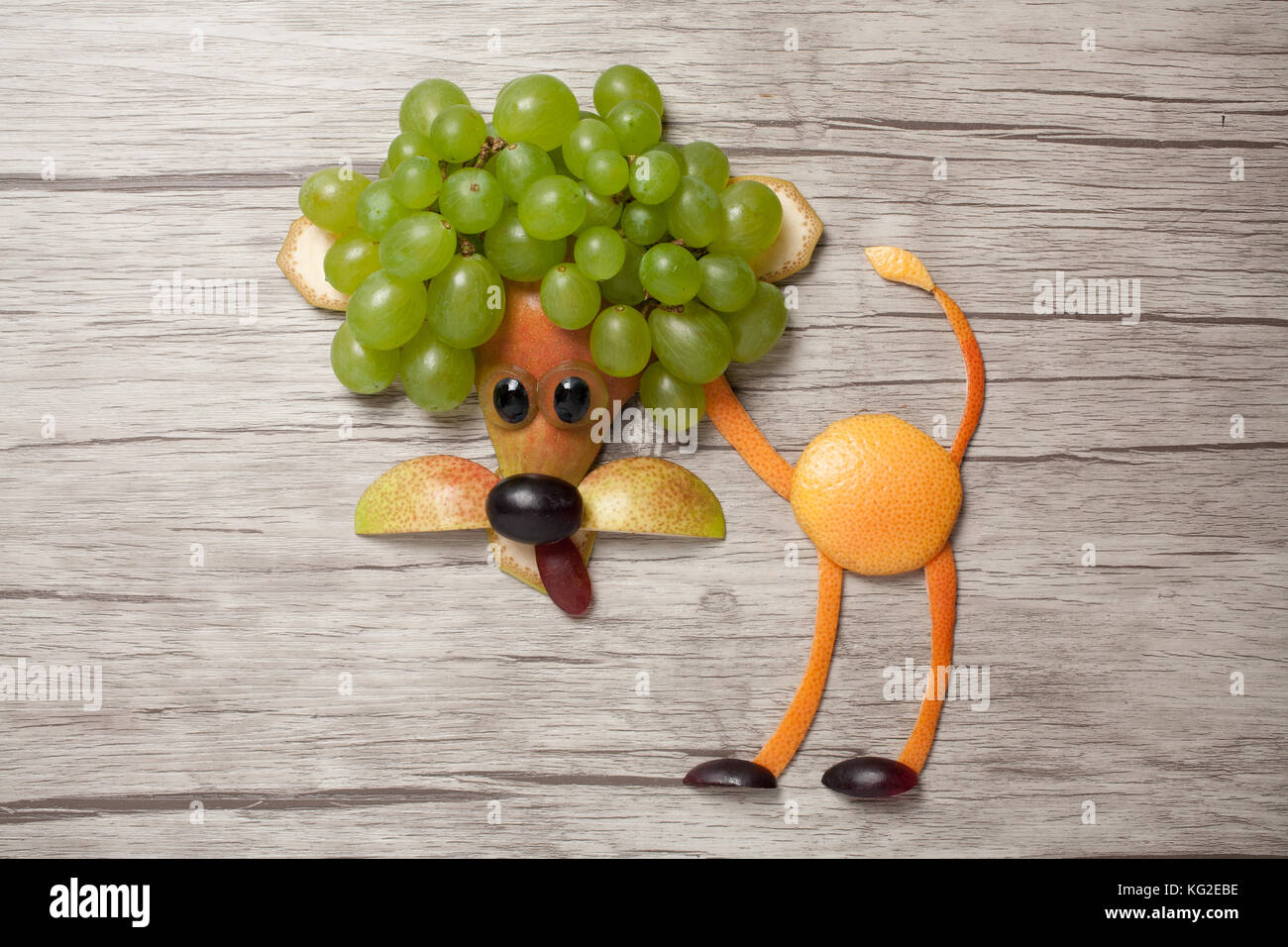 Lion made with grape, orange and pear on wooden background Stock Photo ...