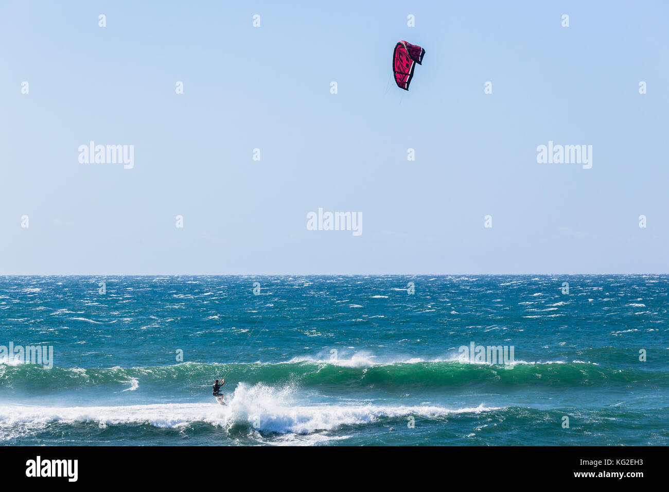 Kite surfer heads out towards ocean horizon through waves Stock Photo ...