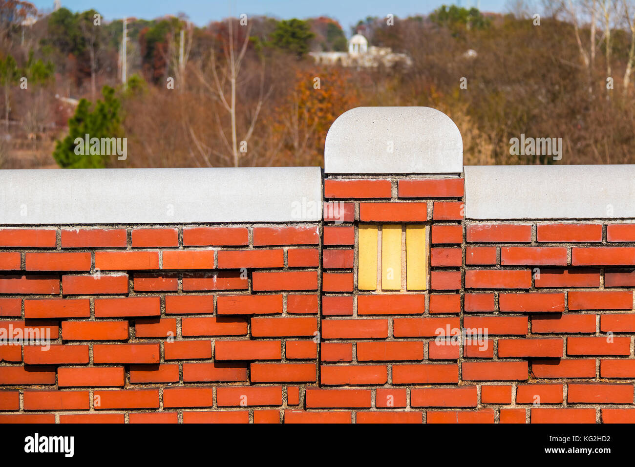 The red brick fence closeup and trees of the park behind it in sunny ...