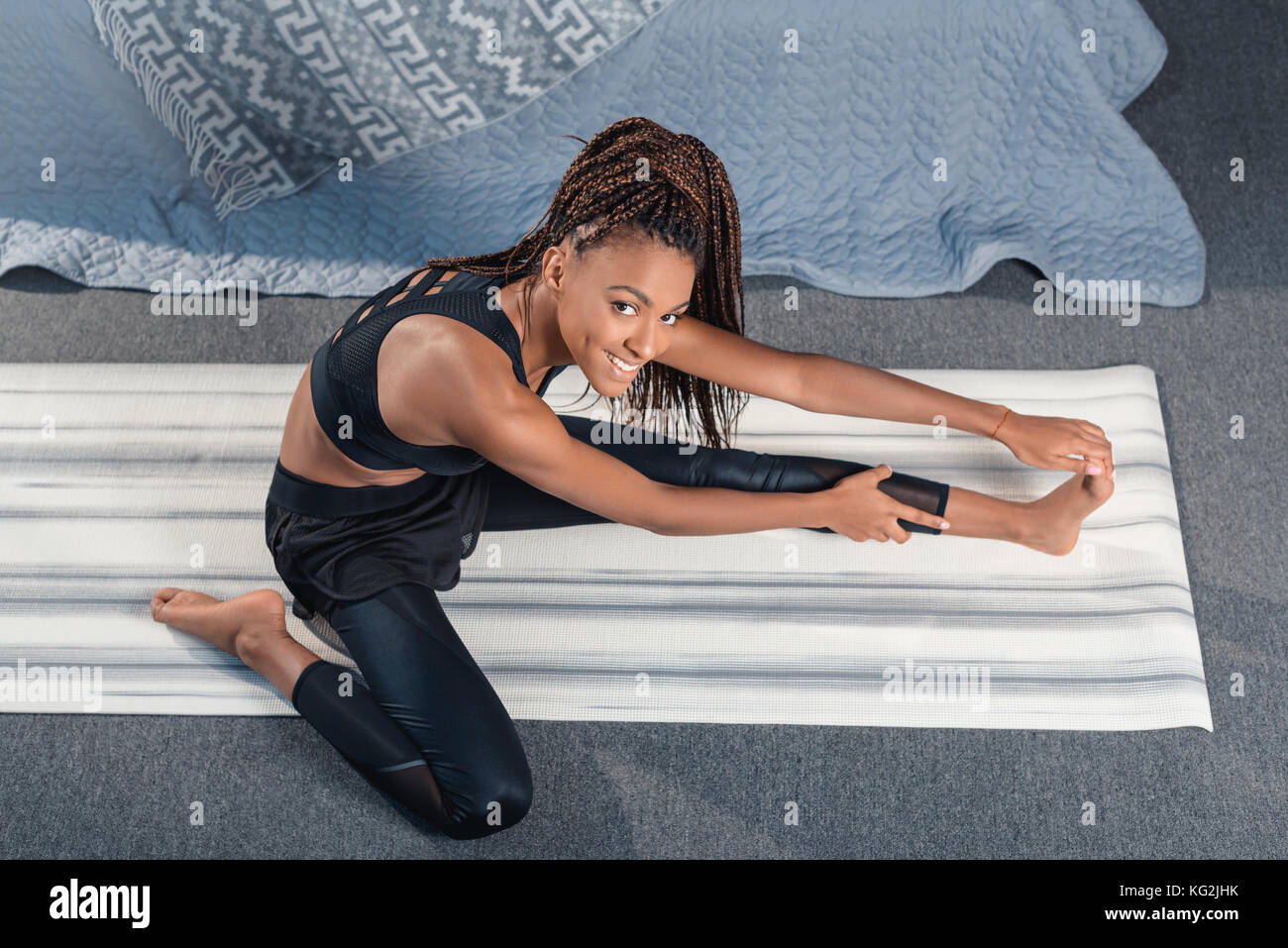 woman stretching leg on yoga mat Stock Photo - Alamy