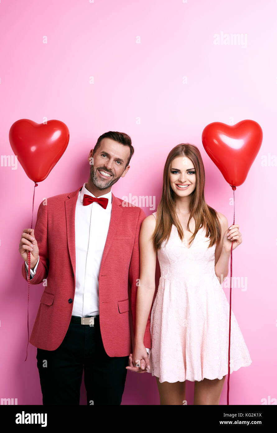 Affectionate couple with heart shape balloons holding hands Stock Photo ...