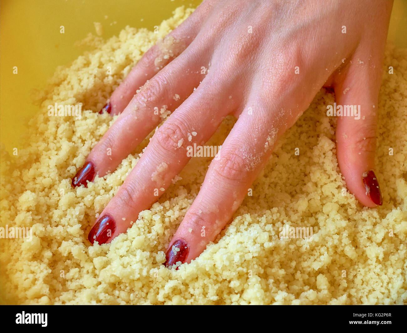 Close look at the hand of a young girl who is preparing the dough for ...