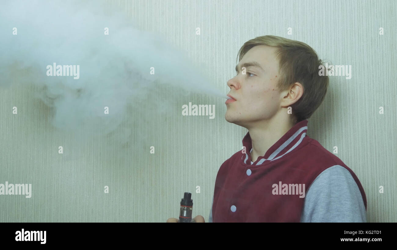 Young man vaping an electronic cigarette. Vaper hipster smoke vaporizer ...