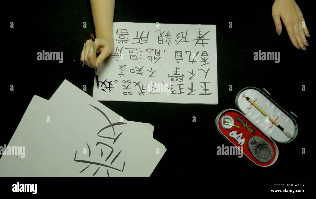 Female hand writing chinese calligraphy using brush and ink on rice ...