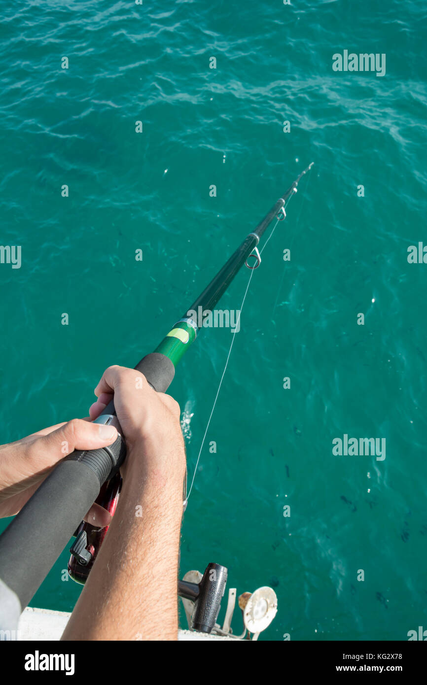 Two Hands Holding the Fishing Rod, Fishing at ocean; turquoise water ...