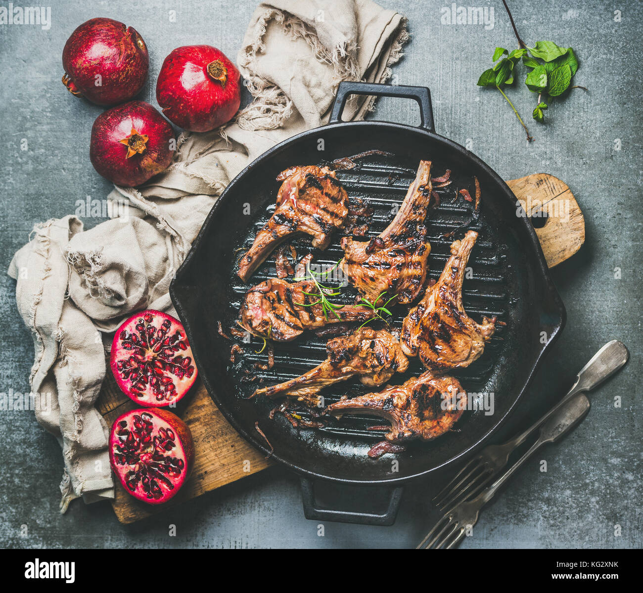 Grilled lamb meat chops served with fresh pomegranates, grey background ...