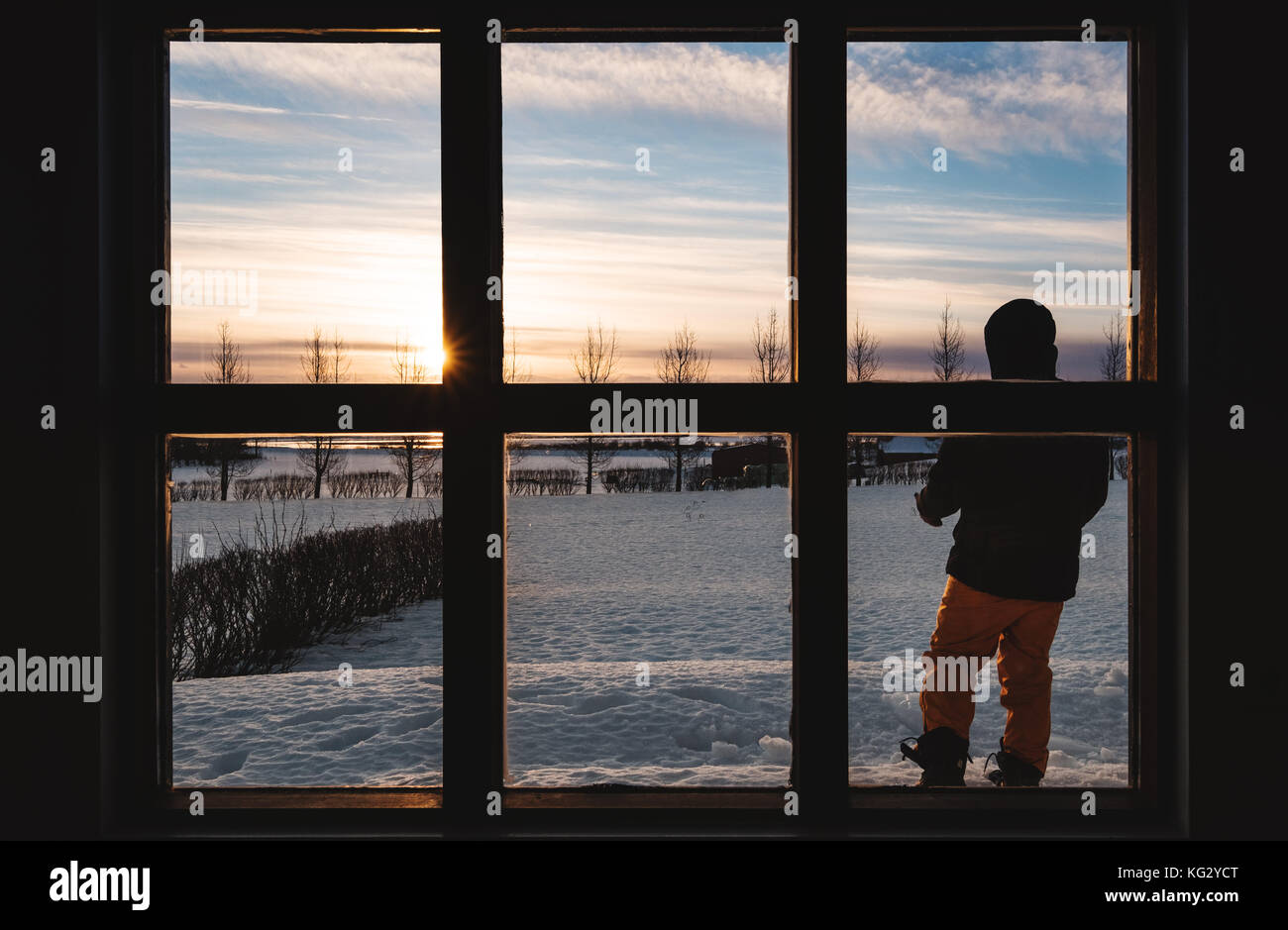 Looking through window in winter sunrise, with a man standing alone in ...