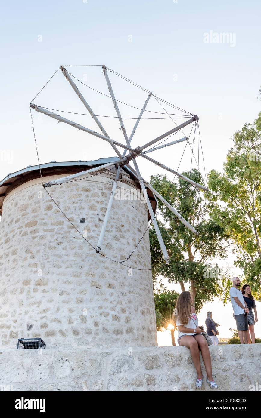 People visit ancient old stone windmills on a sunny day in Alacati town ...