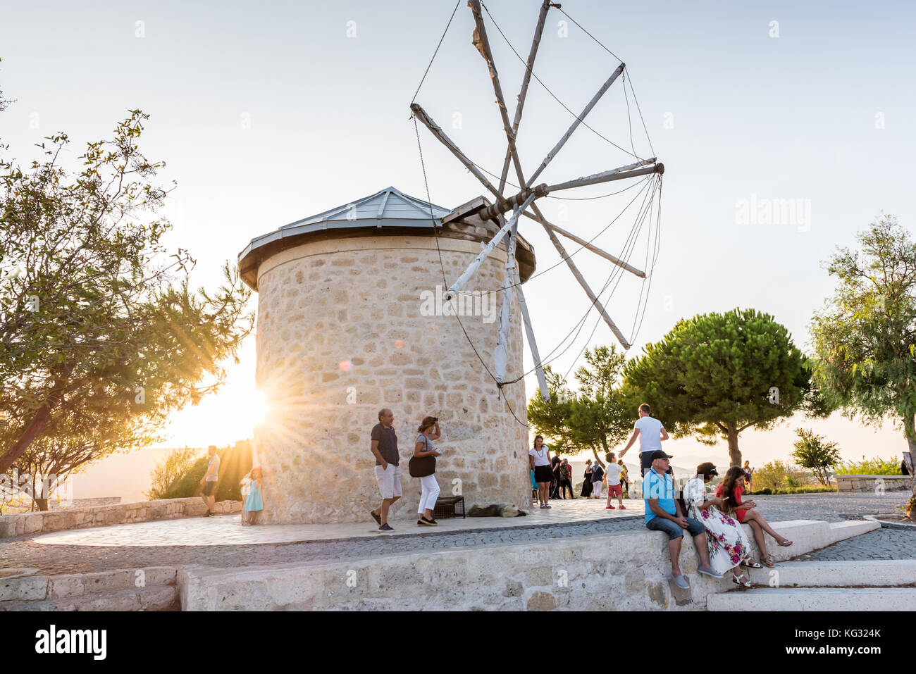People visit ancient old stone windmills on a sunny day in Alacati town ...