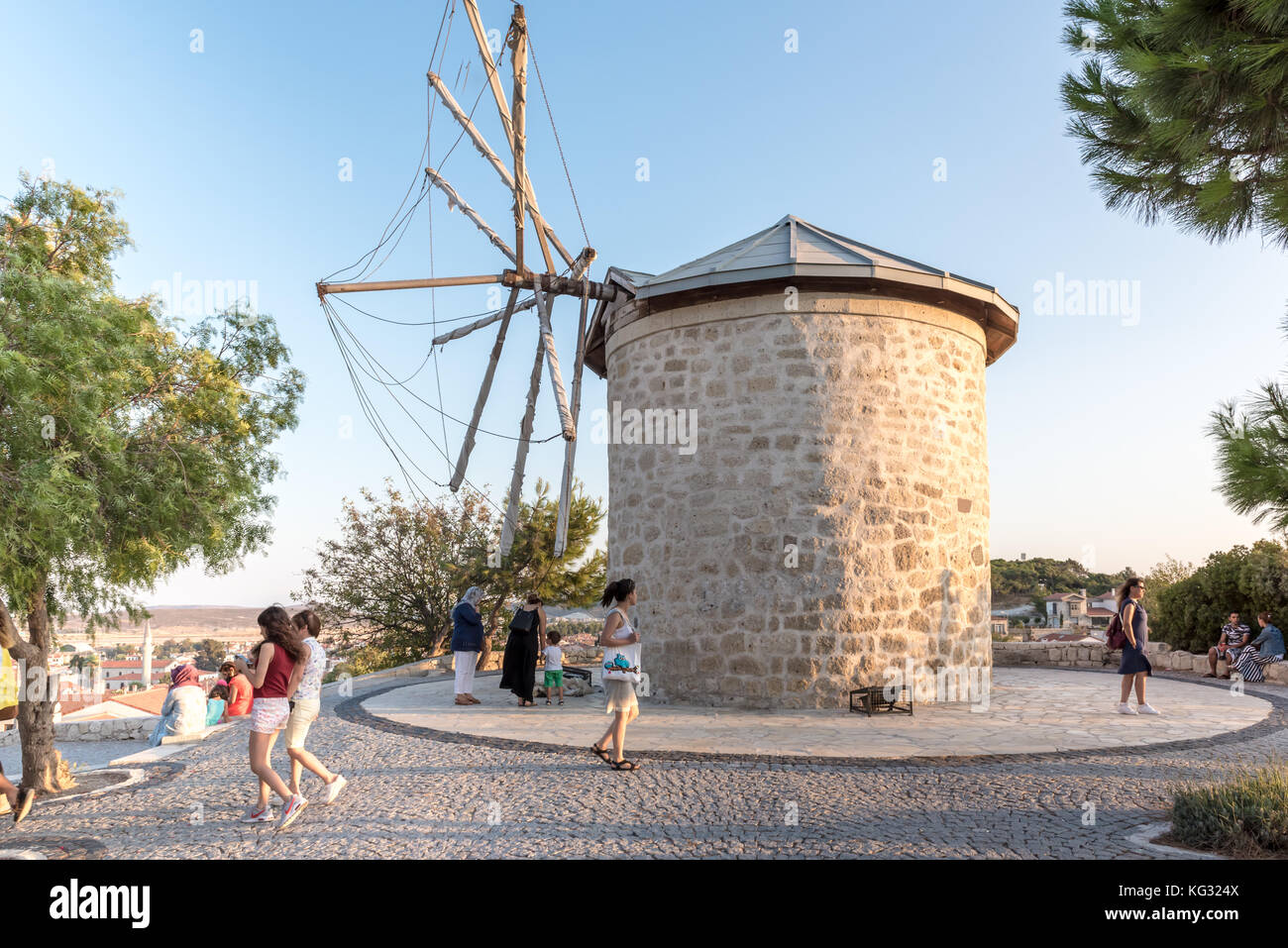 People visit ancient old stone windmills on a sunny day in Alacati town ...