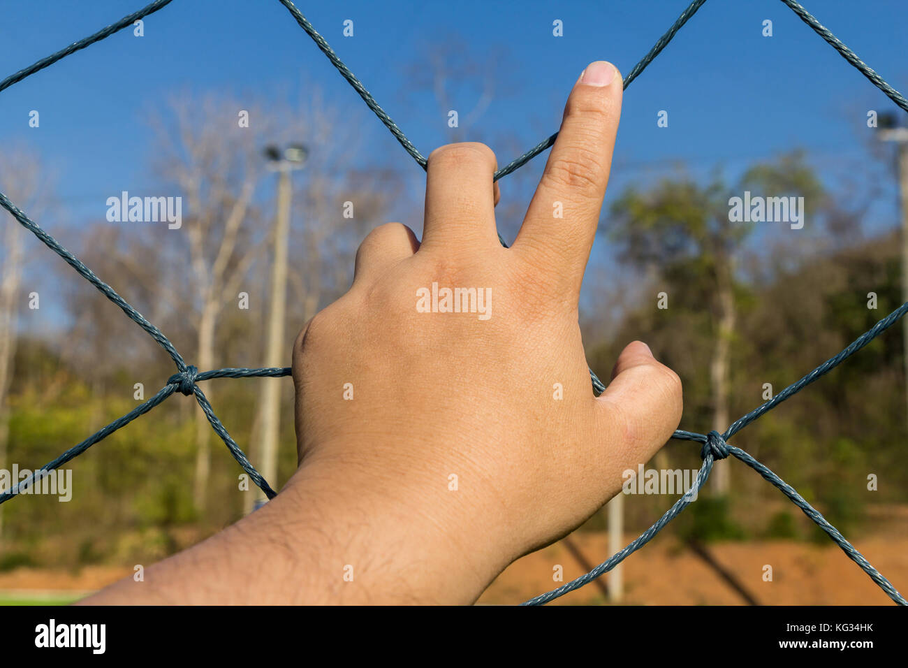 Hand grab the rope mesh fence Stock Photo - Alamy