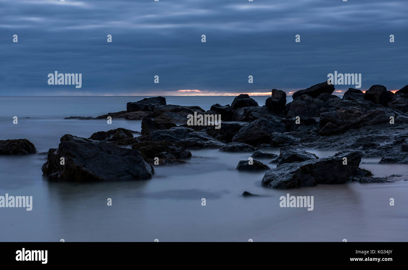 Cornish coast at night with rocks and clouds in the sky, beach at Saint ...