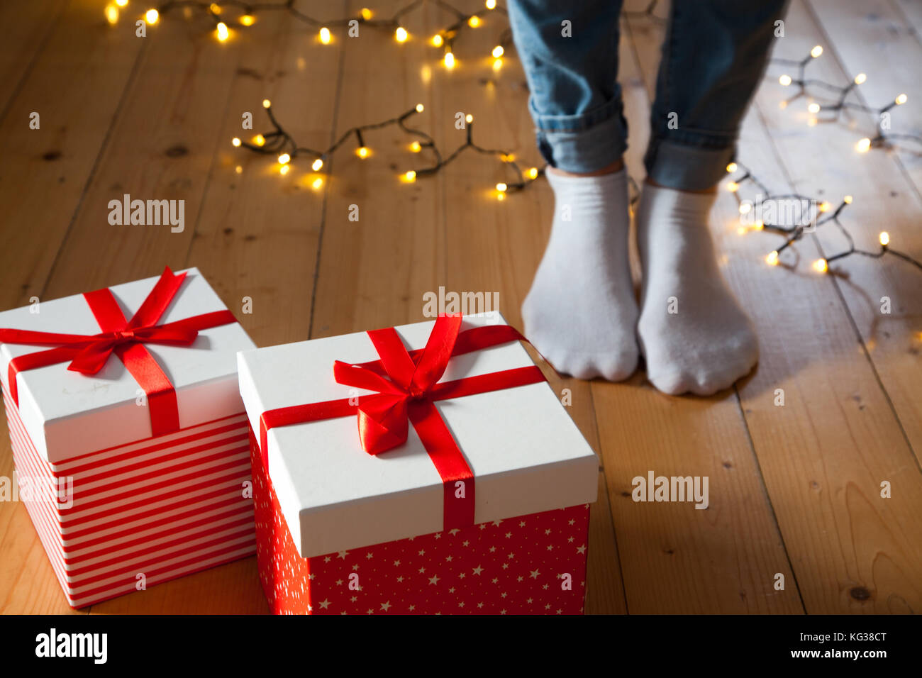 red gift boxes feet and christmas lights on wooden floor Stock Photo ...