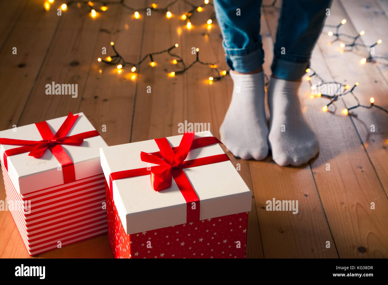 red gift boxes feet and christmas lights on wooden floor Stock Photo ...