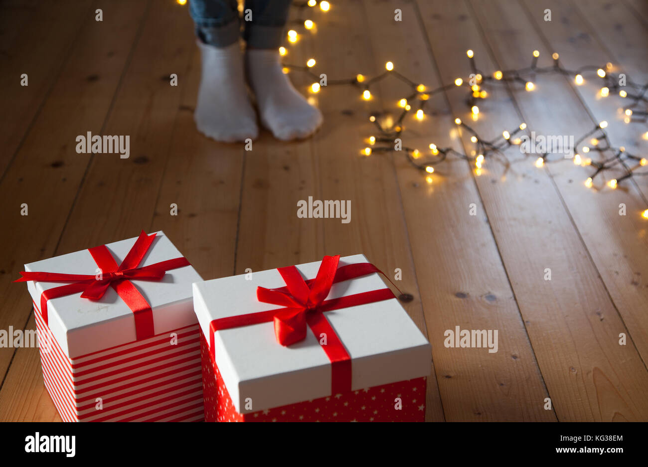 red gift boxes feet and christmas lights on wooden floor Stock Photo ...