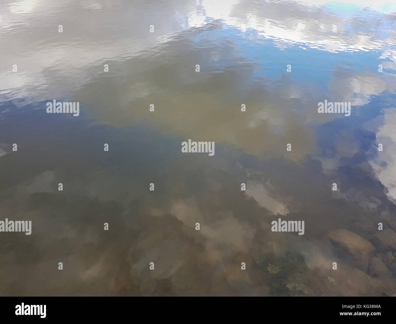 Thunderous blue sky with white clouds is reflected in the water surface ...