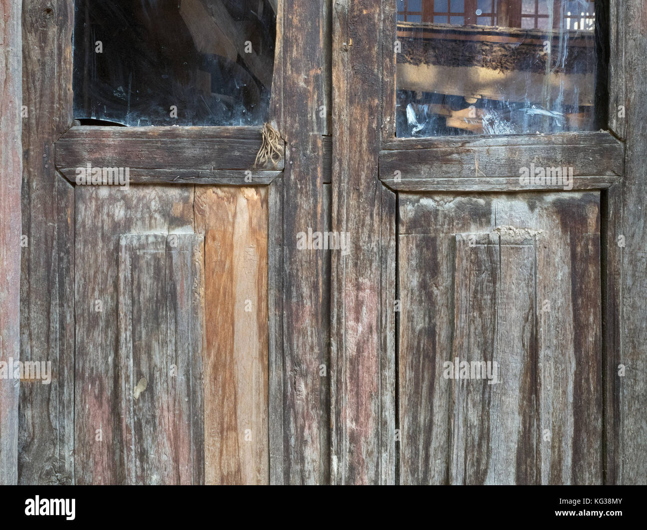 Old wooden cracked door with two panes at the top, a wall of the ...