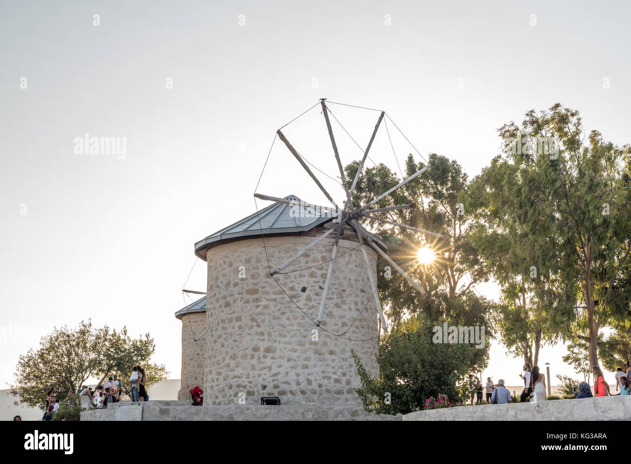 People visit ancient old stone windmills on a sunny day in Alacati town ...