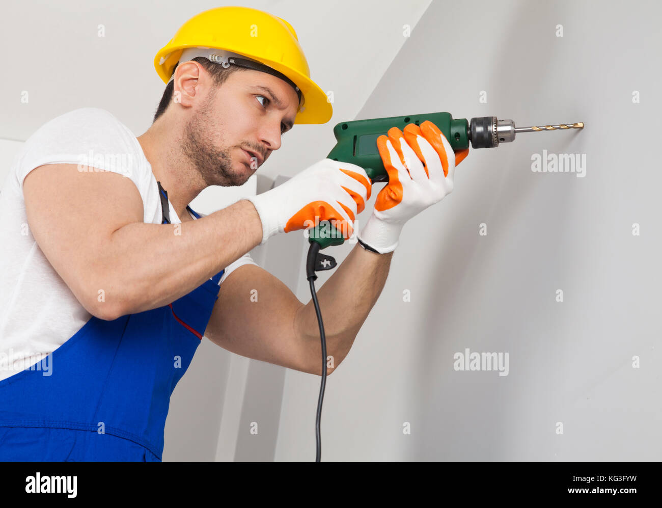 Young man using power drill on wall at home Stock Photo - Alamy