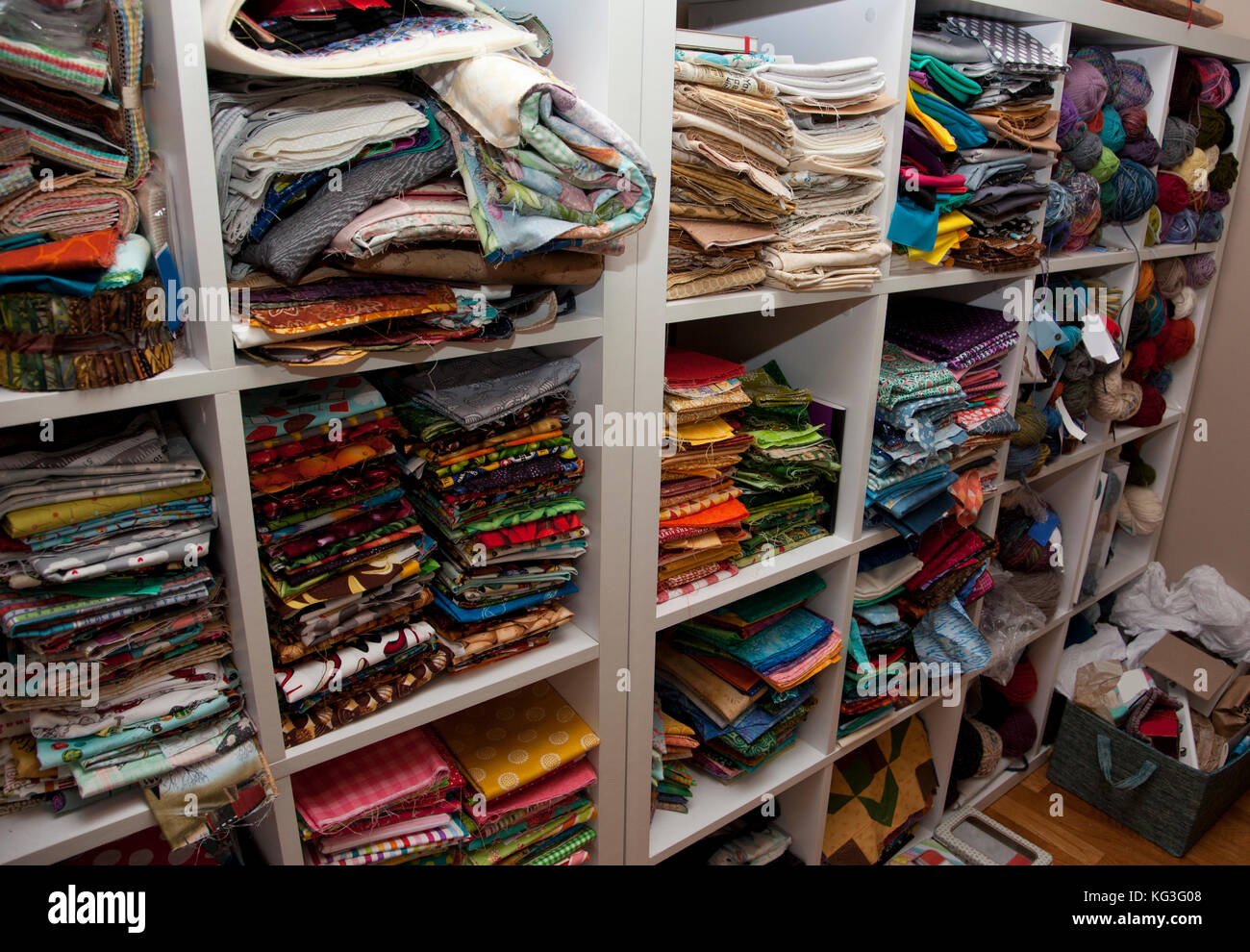 a wall full of shelves of colorful sewing and quilting fabric and ...