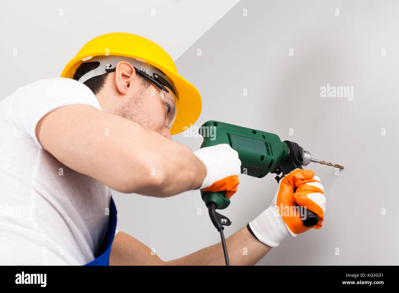 Young man using power drill on wall at home Stock Photo - Alamy