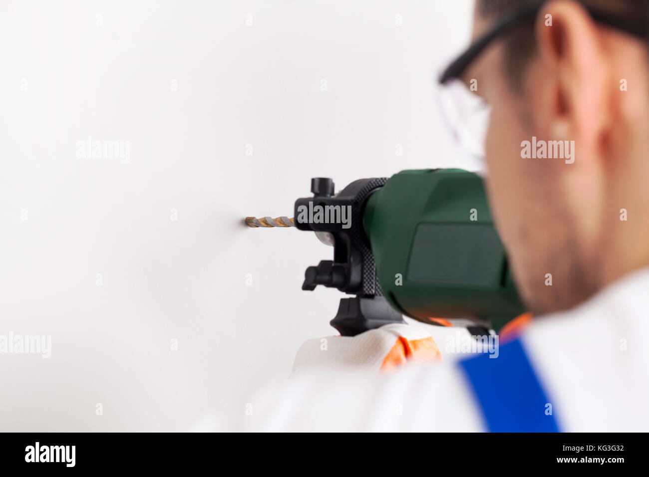 Young man using power drill on wall at home Stock Photo - Alamy