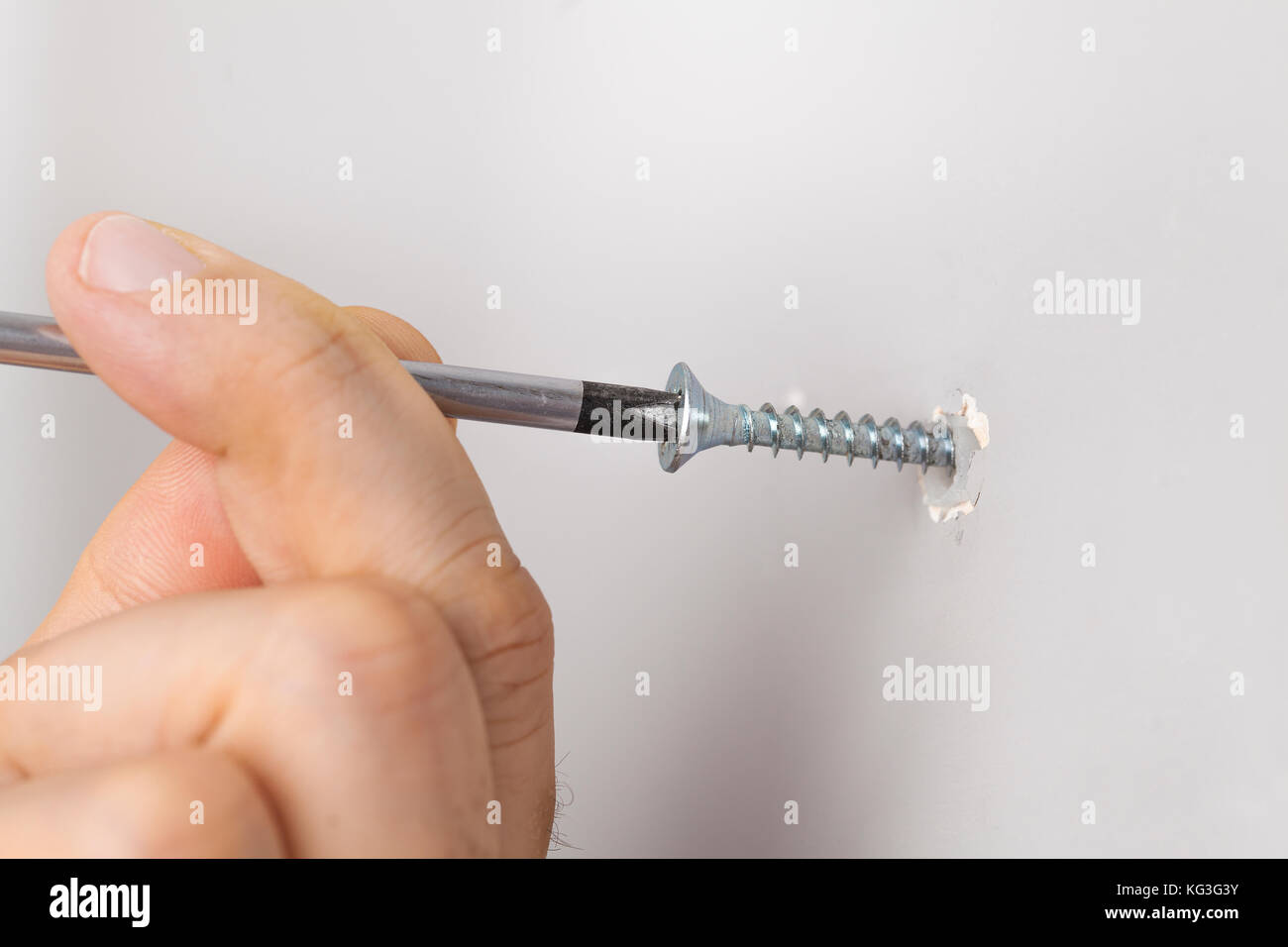 Worker using a screwdriver to put a screw into wall Stock Photo - Alamy