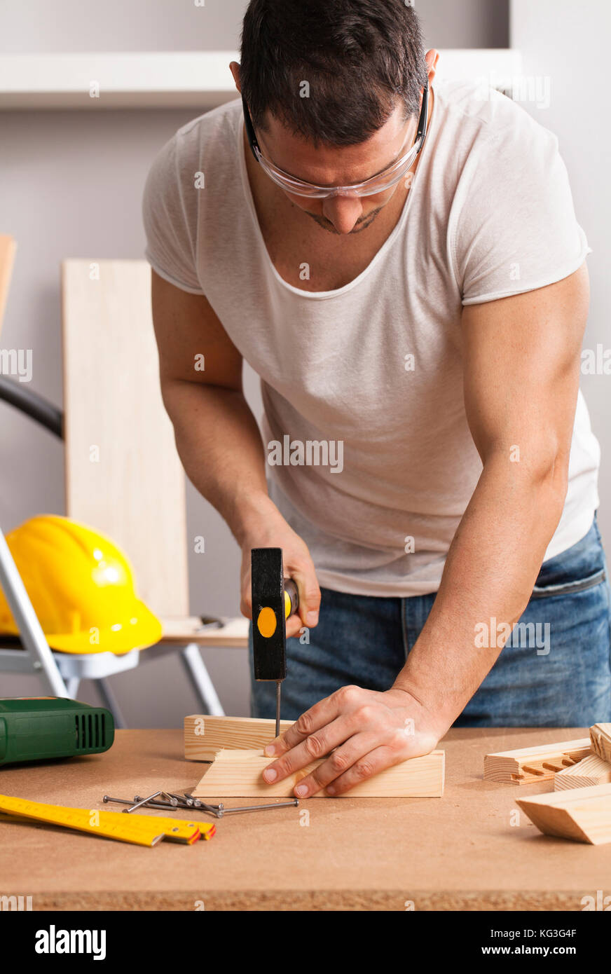 Carpenter hammering nail on timber in workshop Stock Photo - Alamy