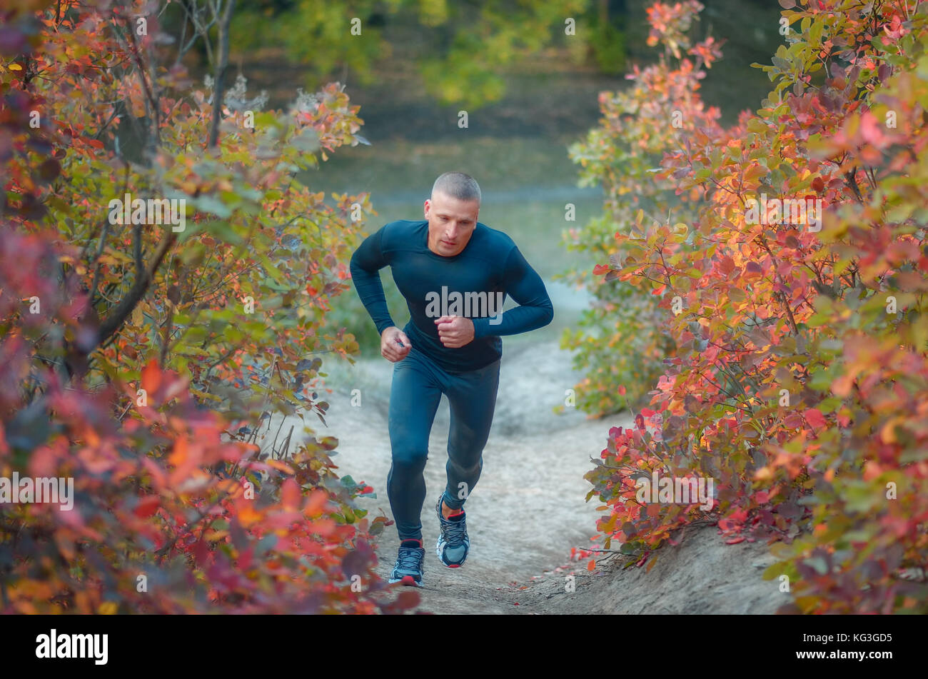 A young muscular jogger in a black leggins and shirt runs on the ...