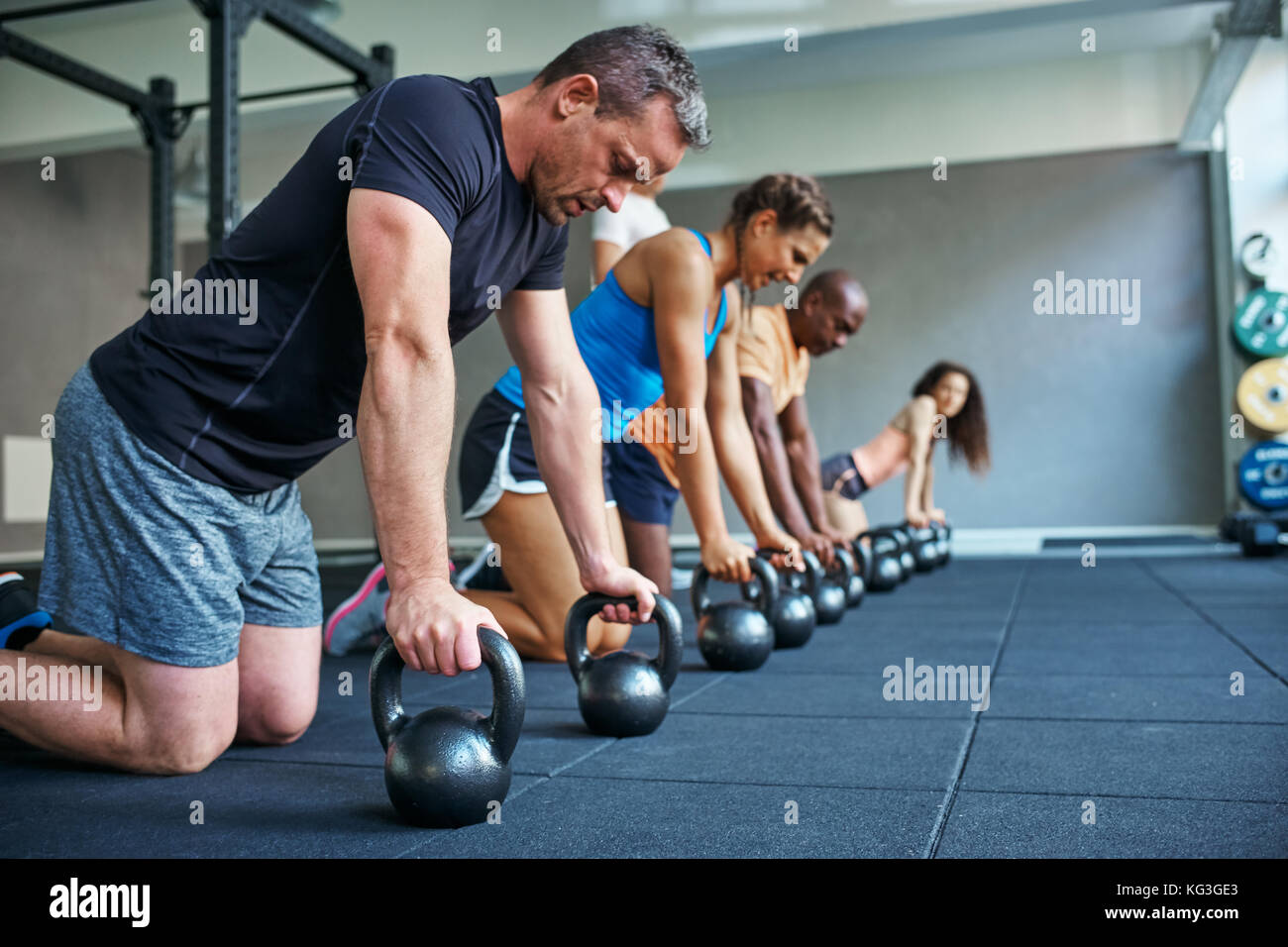 Focused group of fit people working out together on the floor with ...