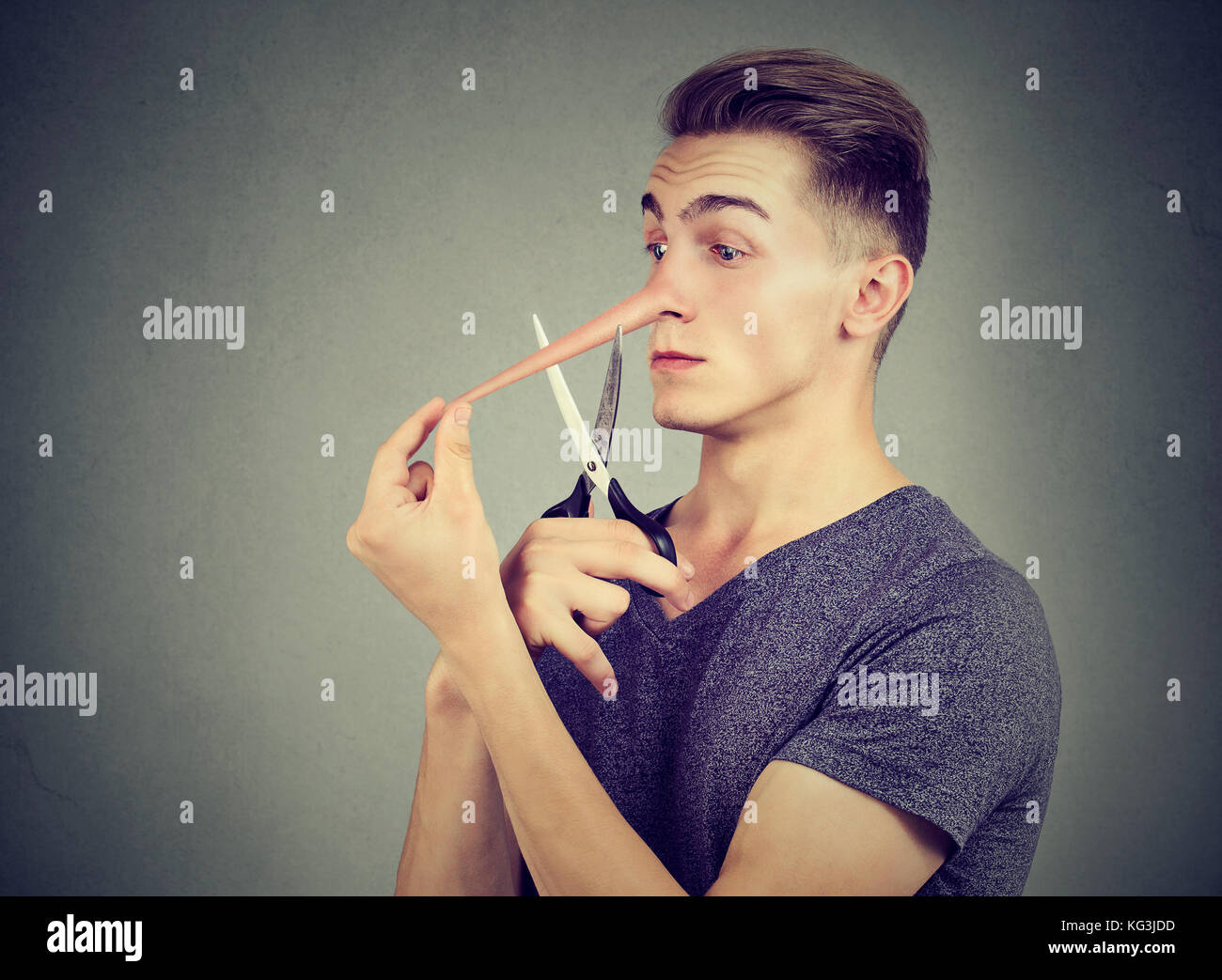 Worried liar man wants to cut his long nose isolated on gray wall ...