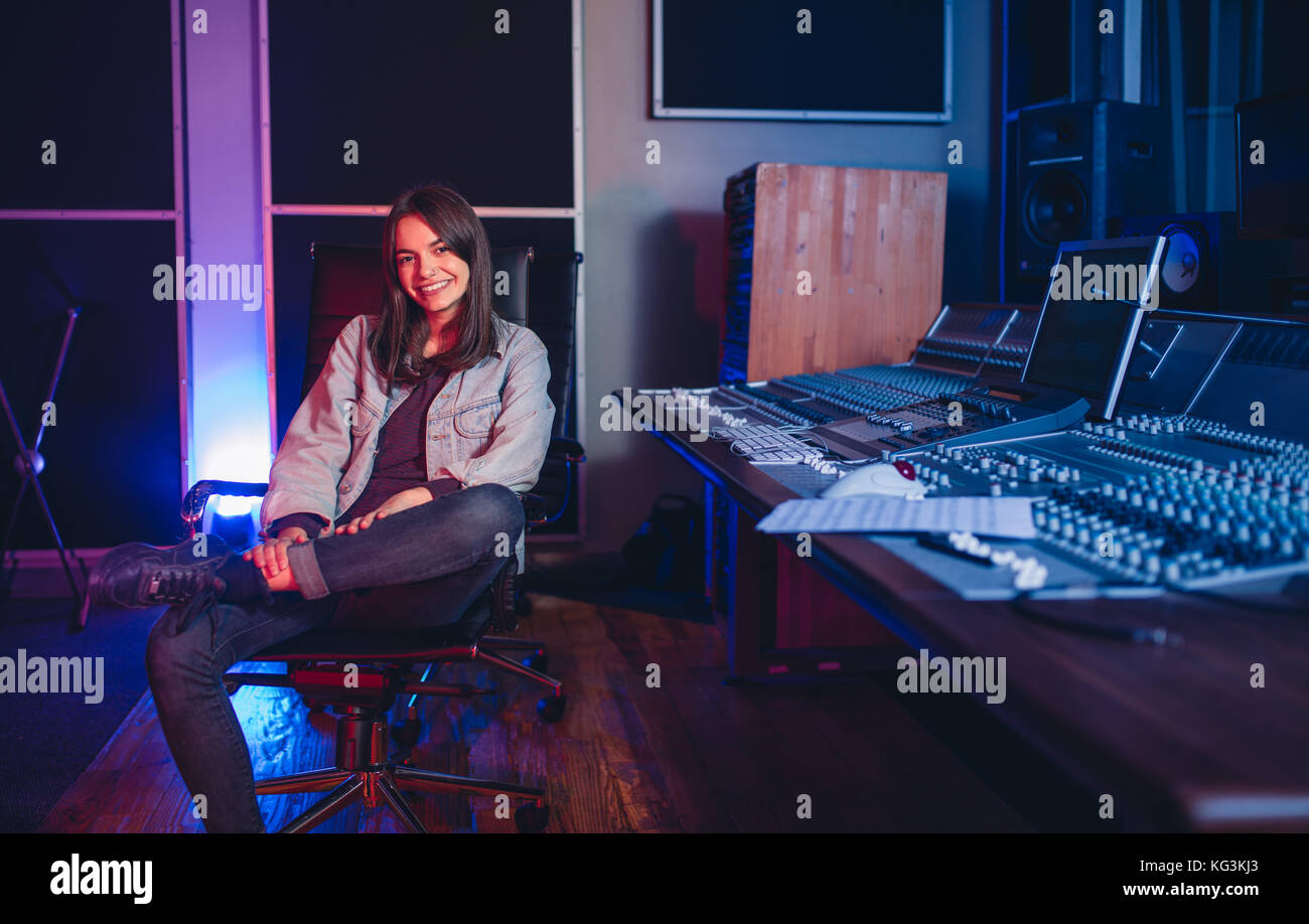 Happy young woman sitting in sound recording studio. Female music ...