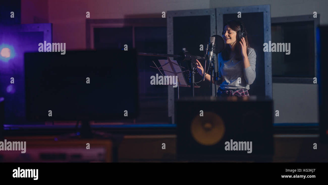 Woman recording a song in music studio. Female playback singer ...