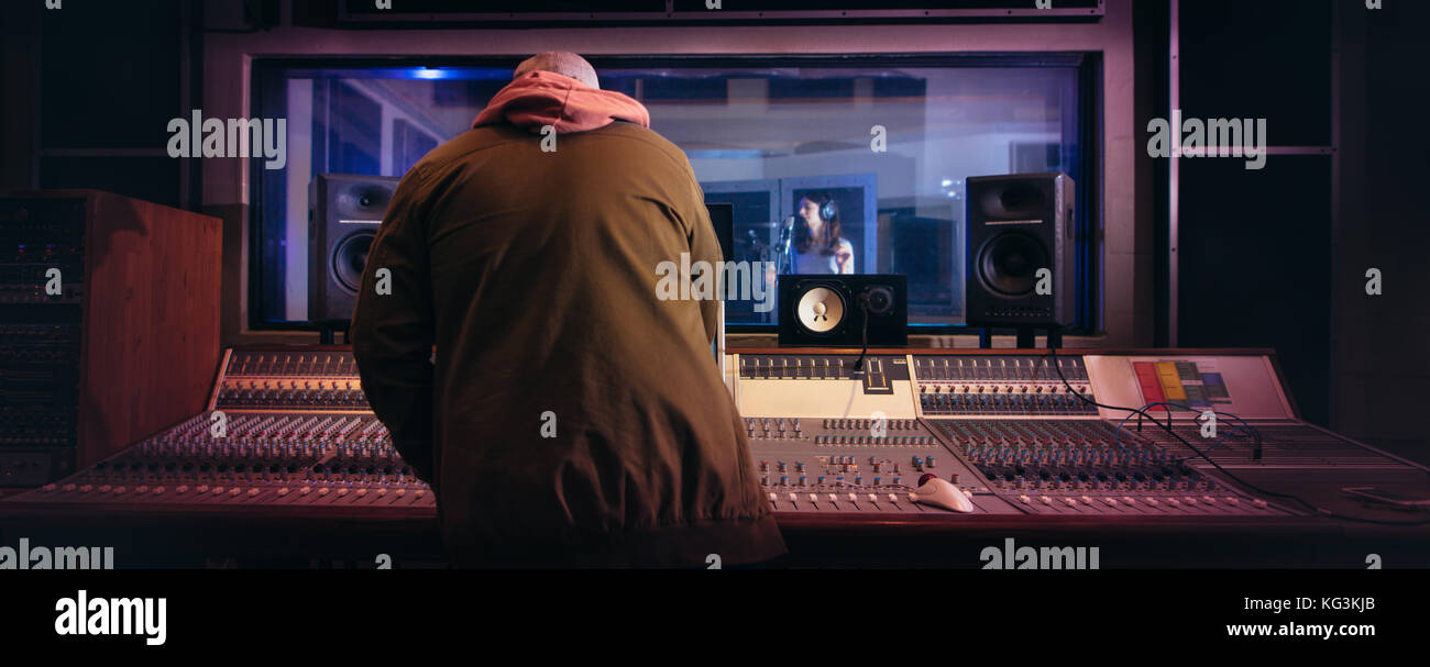 Sound engineer working at audio control panel with singer singing in ...