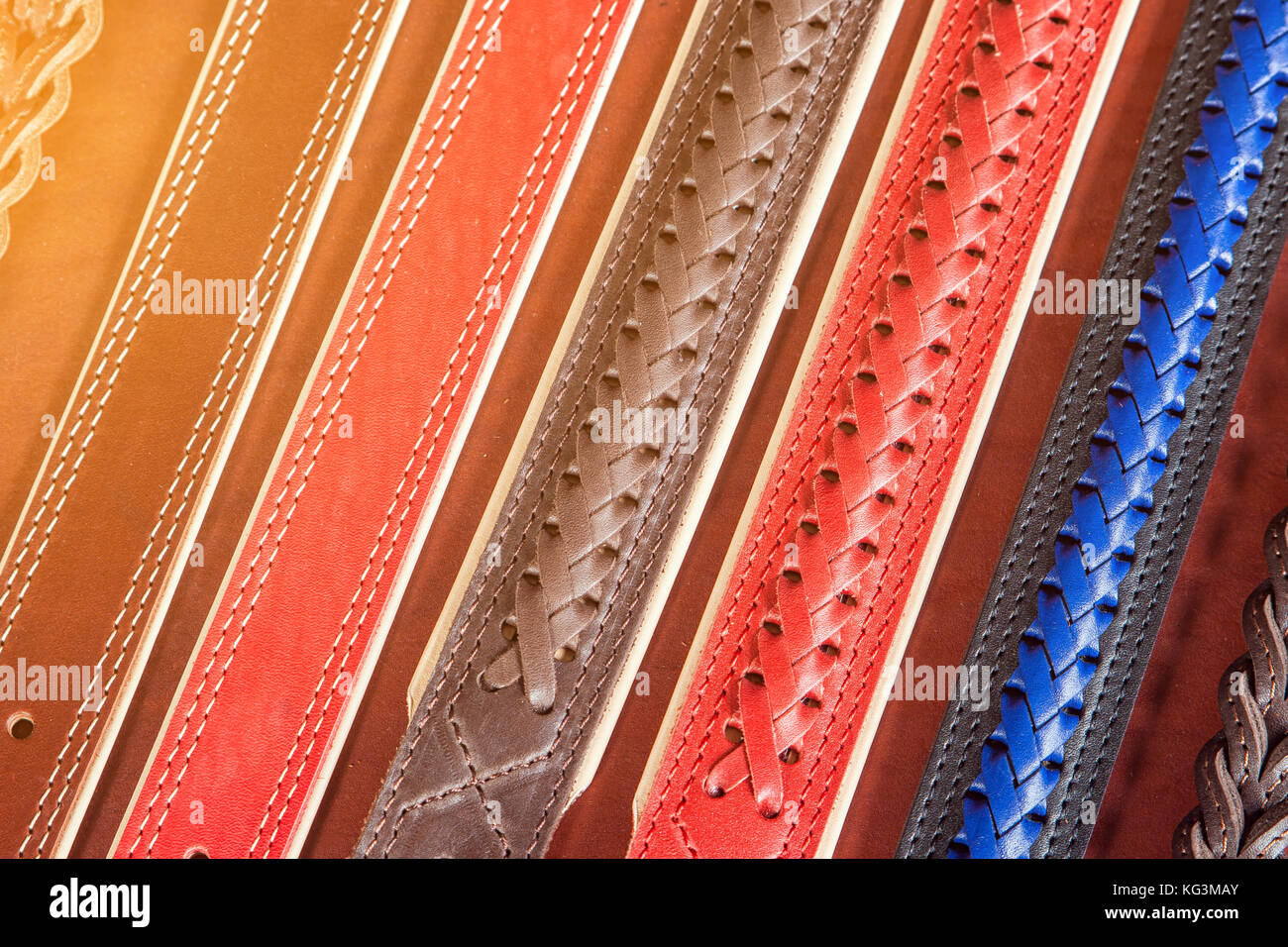 A close-up of narrow belts made of genuine red, blue and brown leather ...