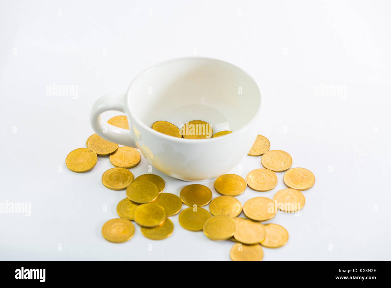 Golden coins in a white cup of coffee on the white background, saving ...