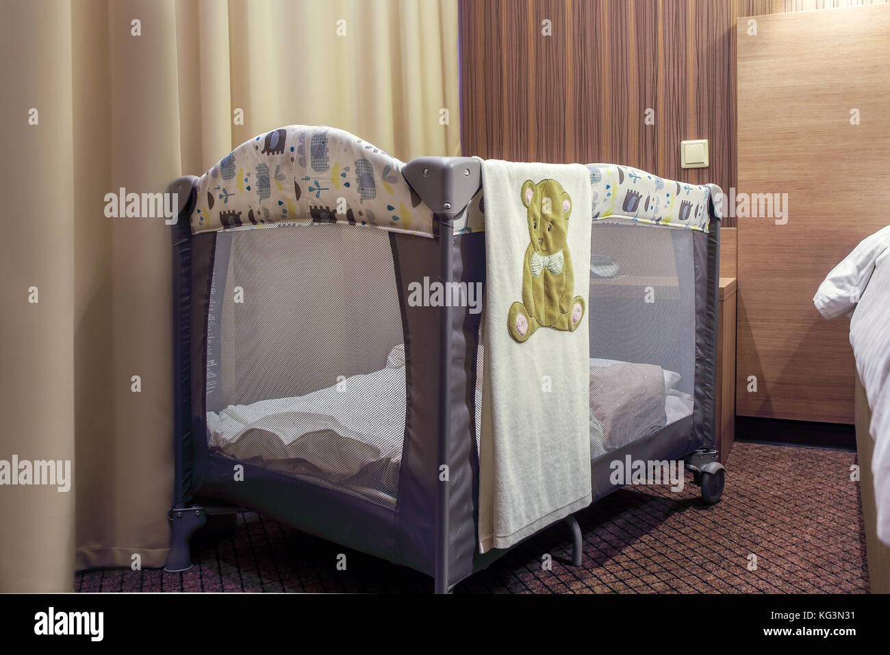 A gray portable baby bed for newborns on wheels, decorated with prints ...