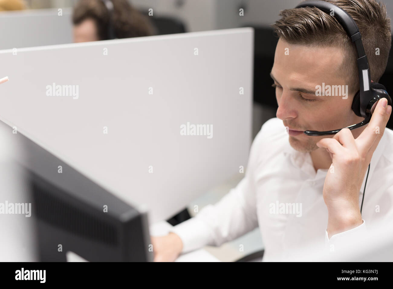 young smiling male call centre operator doing his job with a headset ...