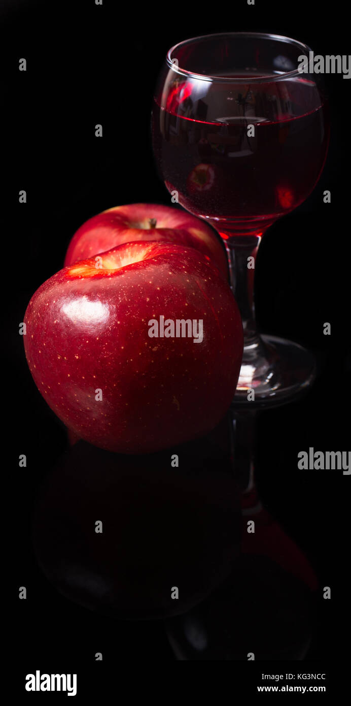 Apples and glass of wine on a black background. Red apples and red wine ...