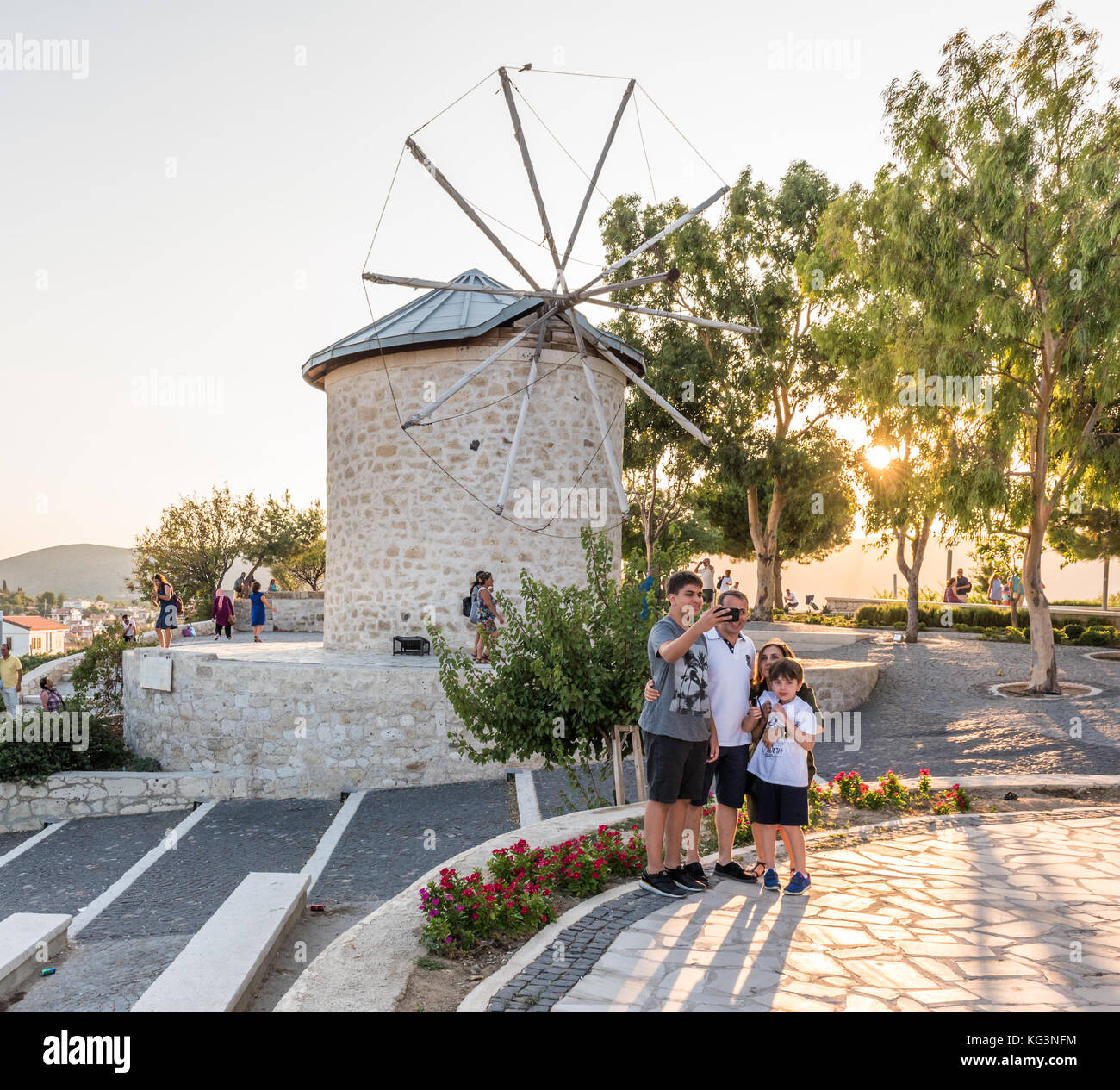 People visit ancient old stone windmills on a sunny day in Alacati town ...