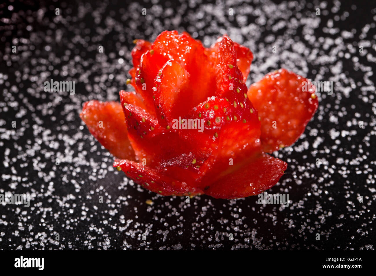The rose which is cut out from ripe strawberry on a black plate, is ...
