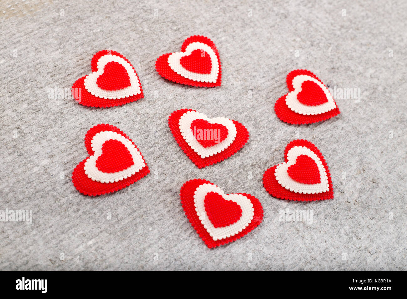 Red hearts on a gray background. A scattering of hearts from red fabric ...