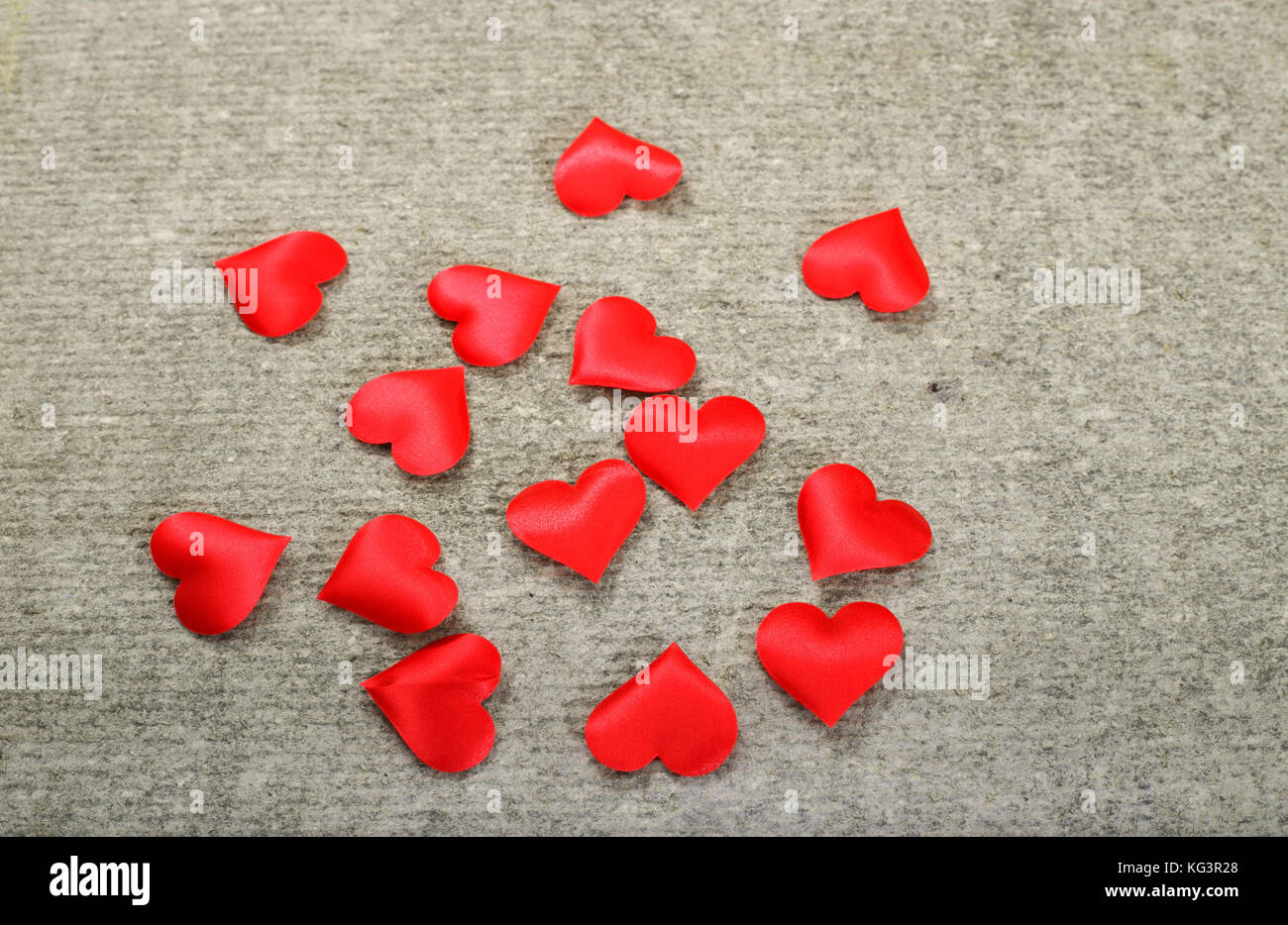 Red hearts on a gray background. A scattering of hearts from red fabric ...