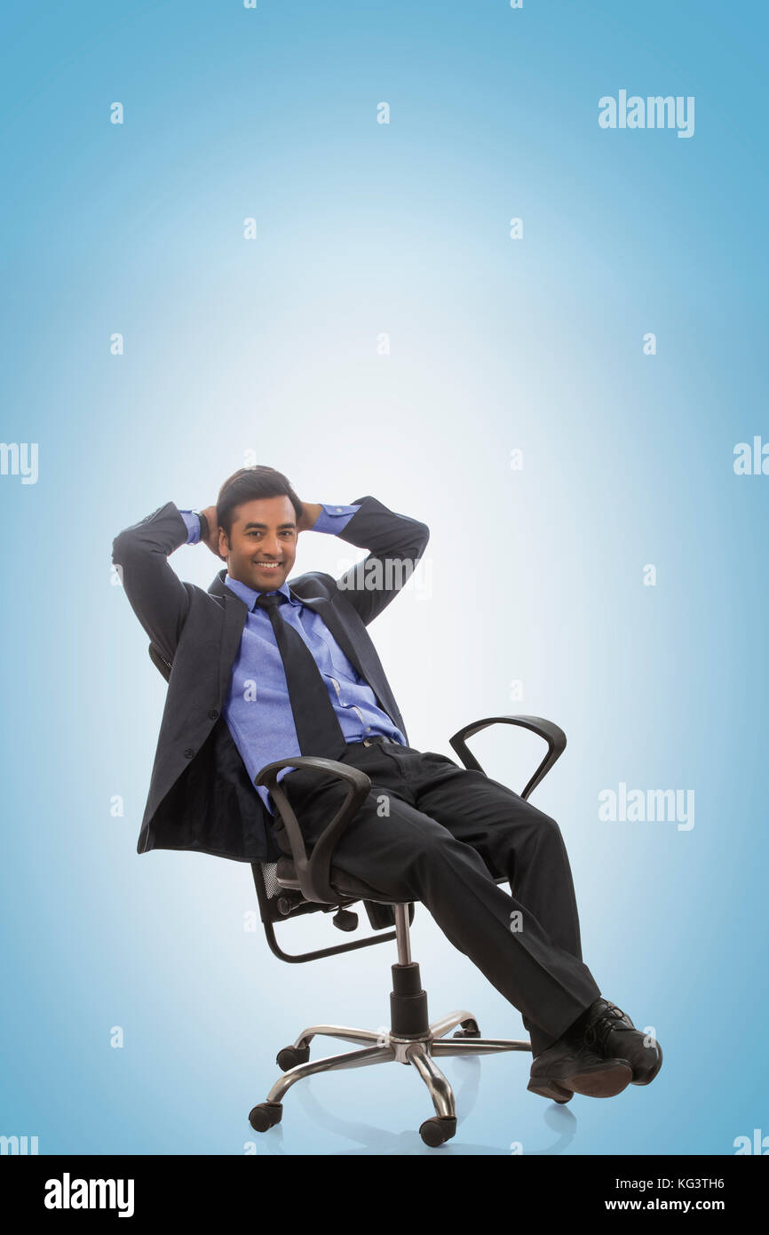 Business man relaxing on chair with hands behind head Stock Photo - Alamy